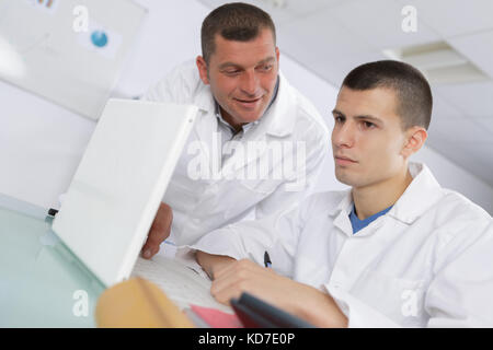 Male teacher with notebook and microscope in classroom. Stem education ...