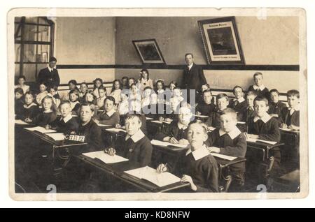 Edwardian postcard of junior school girls in classroom, sitting at ...
