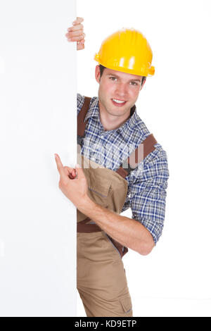 Young man pointing at blank paper sign on lilac background Stock Photo ...