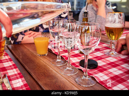 Waiter pouring mineral water from the glass bottle into a glass, food concept, close up Stock ...