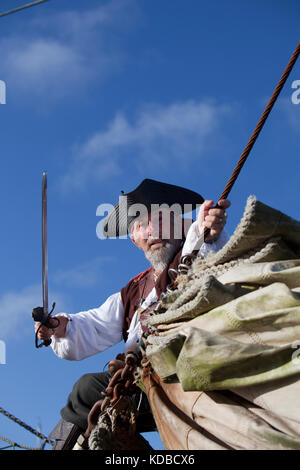 Pirate standing on the bowsprit of old ship with sword drawn in ...