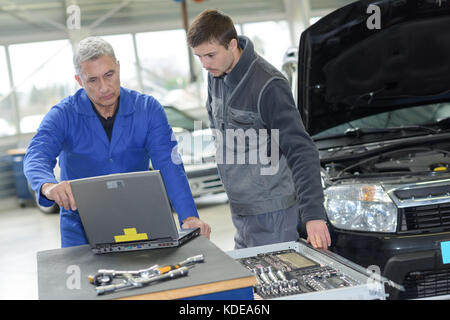 auto mechanic teacher and trainee performing tests at mechanic school ...
