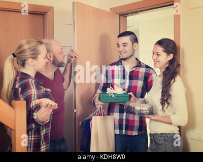 Family couple receiving visitors with the gifts at home Stock Photo - Alamy