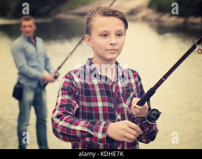 Portrait of smiling teenager boy casting line for fishing on lake Stock ...