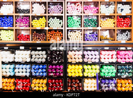 Paraffin candles lying on shelf in shop. Variety yellow and red aroma ...