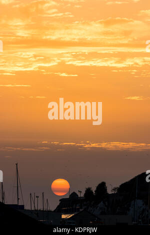 England, Ramsgate. Sunset over Ramsgate seen from the harbour. Sun is ...