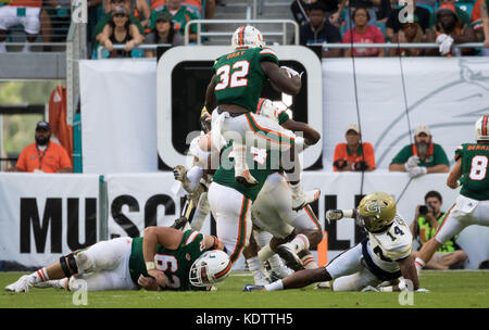 A defensive lineman jumps over an offensive lineman during a college ...