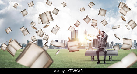 Many old books falling from above and student guy sitting on bench ...