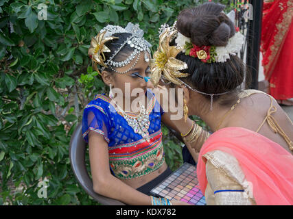 A Guyanese teenager fixing the hair and makeup of a young Guyanese girl ...