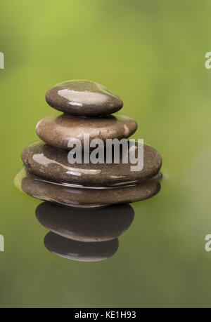 Stacked zen boulders reflected in green water Stock Photo - Alamy