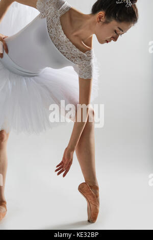 Side view of ballerina bending on grey background Stock Photo - Alamy