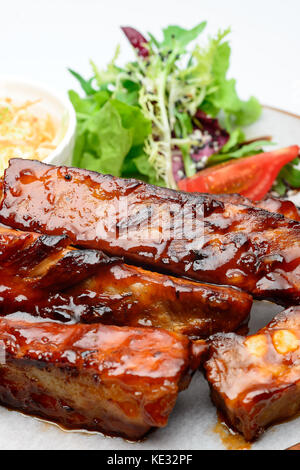 bbq spareribs on the plate with green salad and white sauce Stock Photo ...