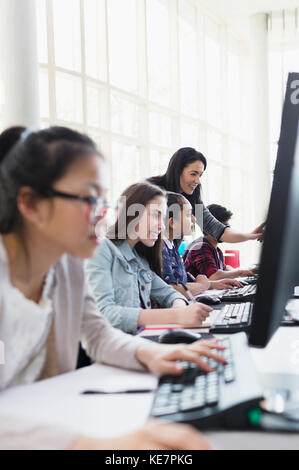 Teacher Helping Students Working At Computers In Classroom Stock Photo ...