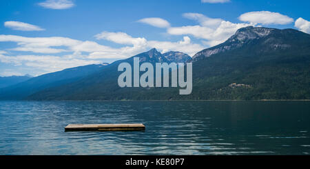 A wooden dock floating in Kootenay Lake in the Selkirk Mountains ...