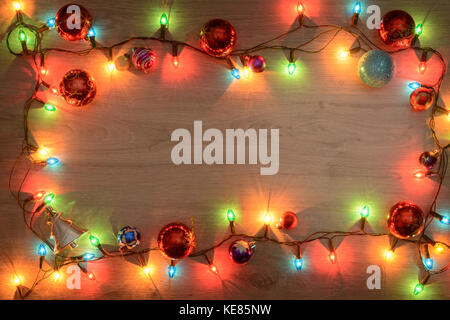 Colorful lighted Christmas garland arranged as frame on wooden table ...