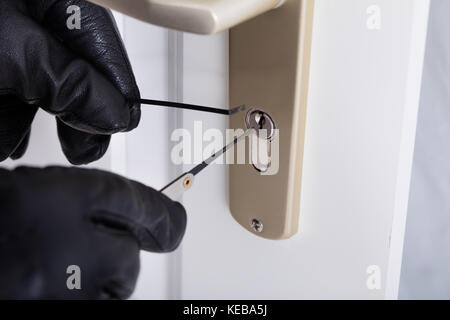 close up of a burglar with gloves picking a lock. Thief with a passkey ...