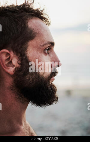 A close up portrait of a bearded surfer at the beach. (minimal focus ...