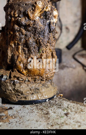 A very old sump pump covered in mineral deposits and mud in front of an ...
