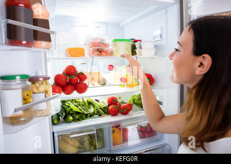young beautiful woman searching for food in the fridge Stock Photo - Alamy