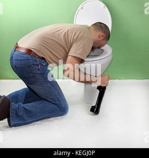 Drunk man throw up in a toilet with empty beer bottles next to him ...