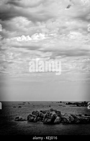 Monochrome photograph of rugged coastal rocks with sharp cracks and ...