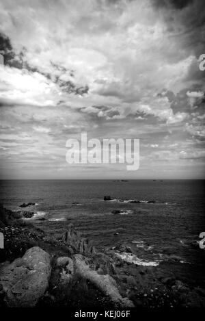 Monochrome photograph of rugged coastal rocks with sharp cracks and ...