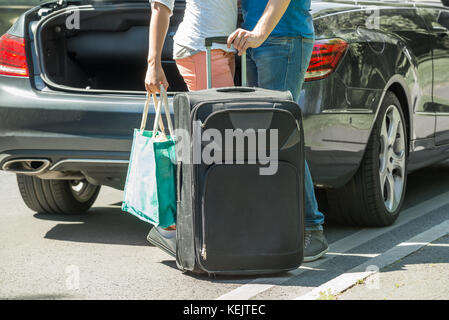 woman putting luggage in the trunk of a yellow cab New York City USA ...
