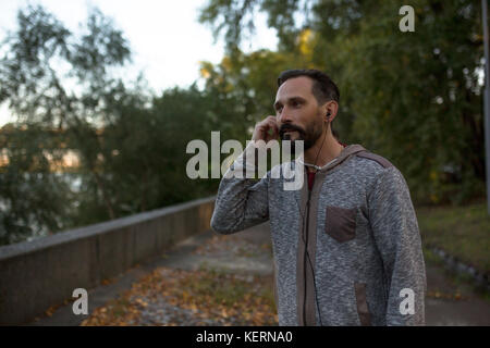 Sportive man setting headphones while jogging Stock Photo - Alamy