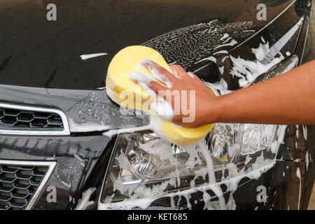 Female hand with sponge and detergent washing glass against blue ...