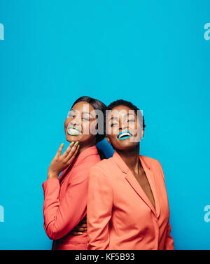 Two friends standing together over pink background thinking looking ...