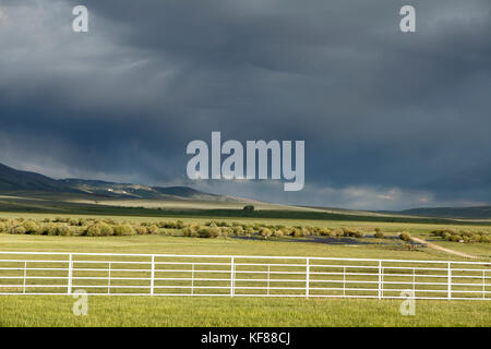 USA, Wyoming, Encampment, a white fenceline and open rolling landscape ...