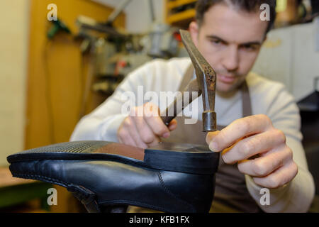 shoemaker hammering on a shoe in workshop Stock Photo - Alamy