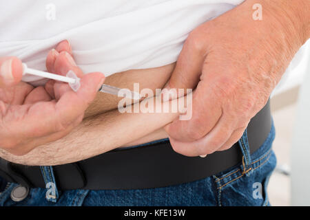 Insulin injection. Diabetic man injecting himself with insulin. He is ...