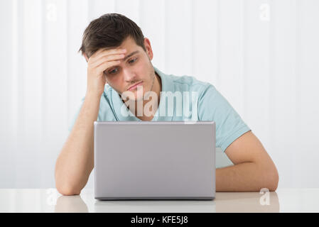 Sad Young Man Working On computer At Desk Stock Photo - Alamy