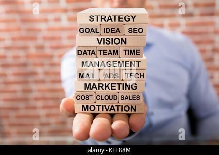 Businessman holding a stack of blocks in the palm of his hand with the ...