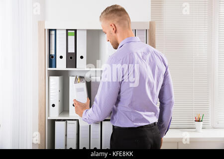 Businessman taking file from shelf in storage room at workplace Stock ...