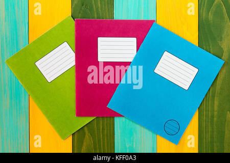 Three exercise books on the colorful wooden background Stock Photo - Alamy