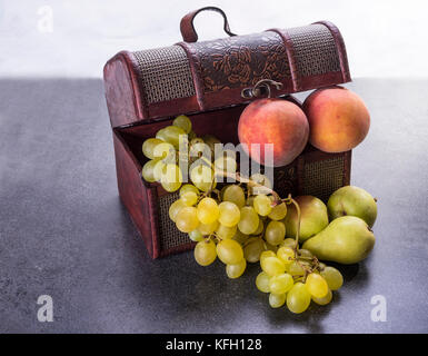 Chest full of fruit like grapes pears peaches and bananas on grungy ...