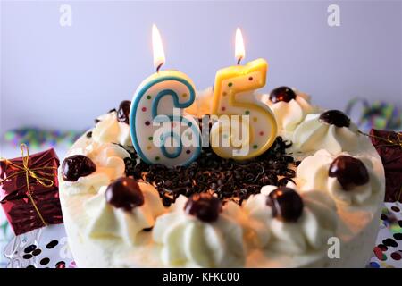 Number 65 birthday celebration candle against a bright yellow ...