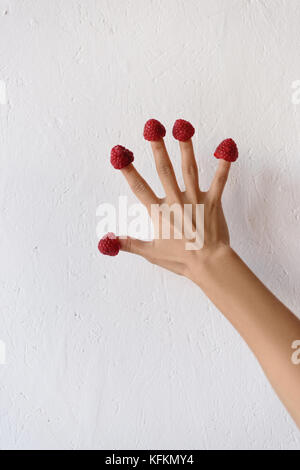 Female hand with raspberries on fingers against white background Stock ...