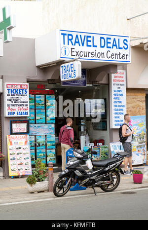 Malia, Crete, Greece. Prospective customers standing outside a travel ...