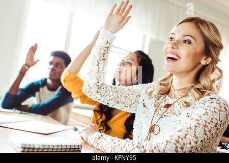 High school students raising hands, in classroom with professor Stock ...