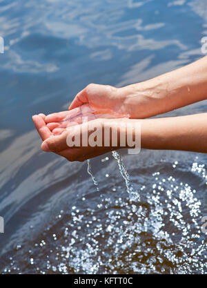 Water pouring out of a young woman's hands Stock Photo - Alamy