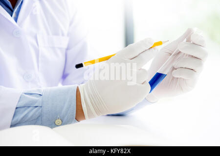 Scientist holding pencil for label on test tube reagent for analysis ...