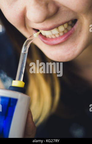 A woman using an oral irrigator in bathroom Stock Photo - Alamy