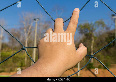 Hand grab the rope mesh fence Stock Photo - Alamy
