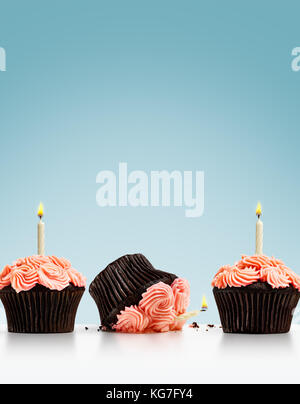 Smashed cupcake in row of cupcakes with candles on blue background ...