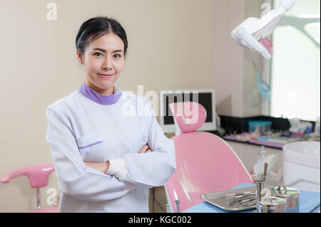 Female dentist crossing arm while standing in front of dental ...
