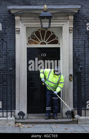 A street cleaner sweeping leaves outside 10 Downing Street in London ...