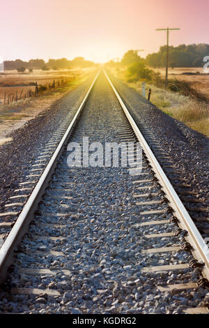 Railroad track sunlit with a beautiful sunset Stock Photo - Alamy